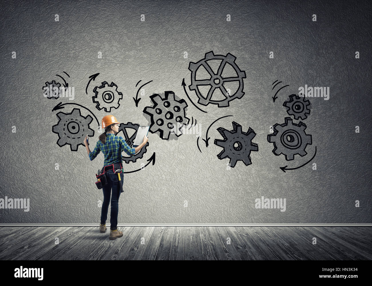 Back view of engineer woman in hardhat and sketched concept of teamwork ...