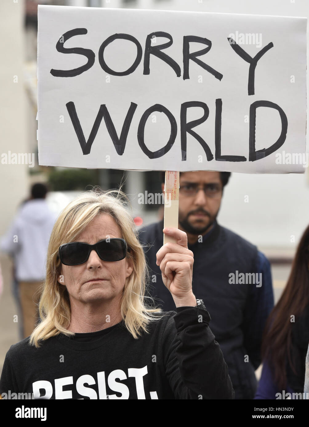 A demonstrator carrying a "sorry world" sign and "resist" shirt at an ...