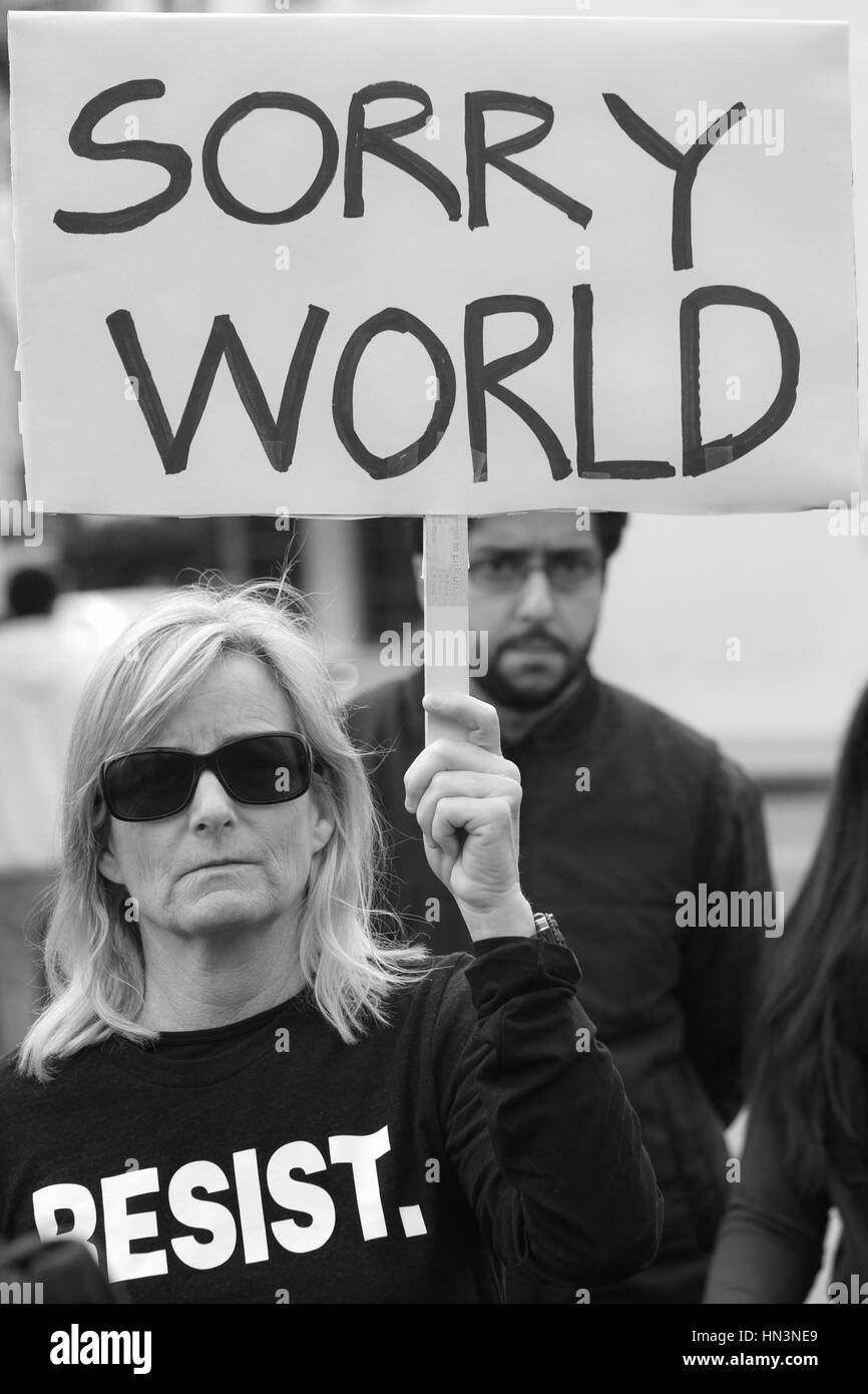 A demonstrator carrying a "sorry world" sign and "resist" shirt at an ...