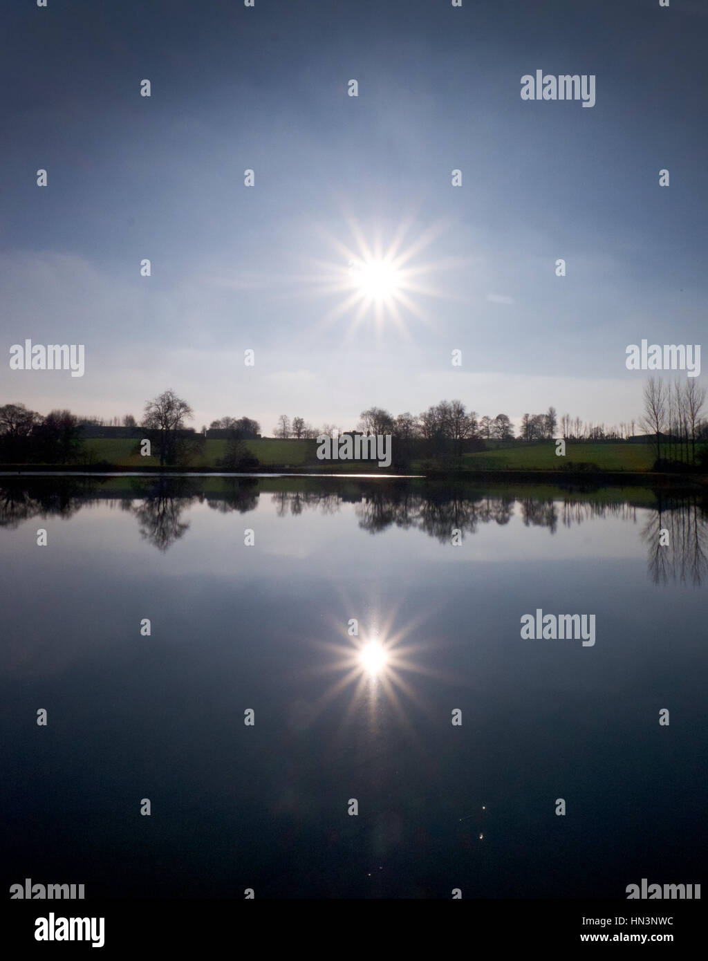 sun shining on a lake with a thin line of green fields in the middle ...