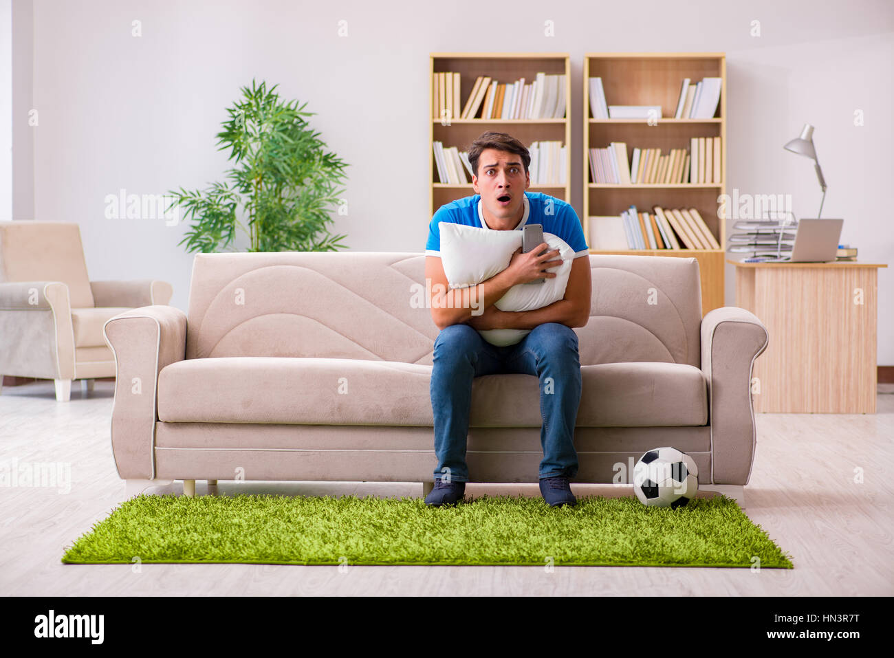 Man watching football at home sitting in couch Stock Photo - Alamy