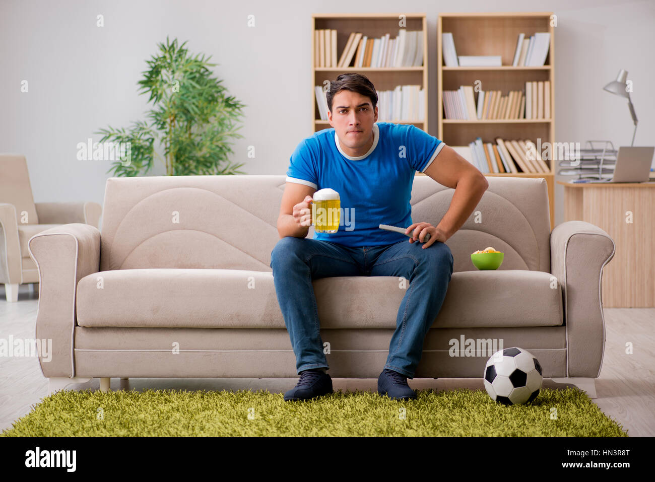 Man watching football at home sitting in couch Stock Photo - Alamy