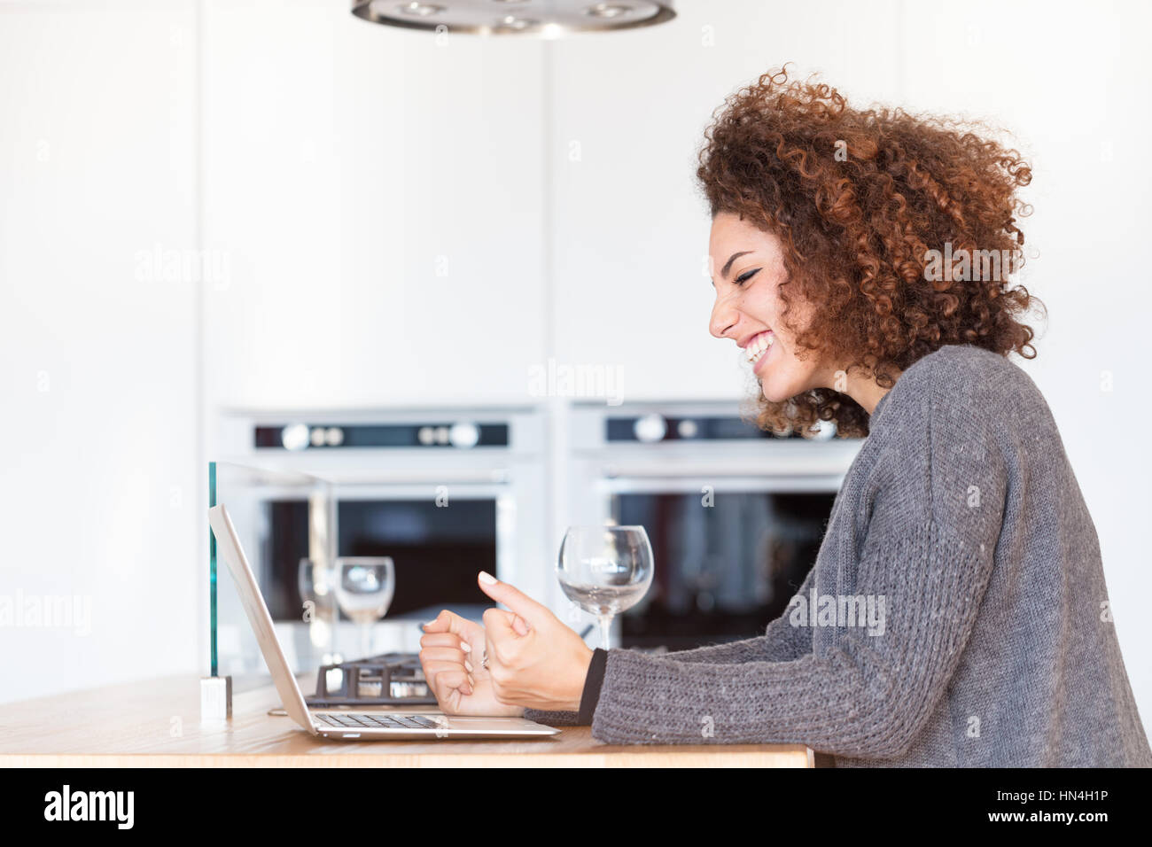 Excited young woman surfing on her laptop clenching her fists in ...