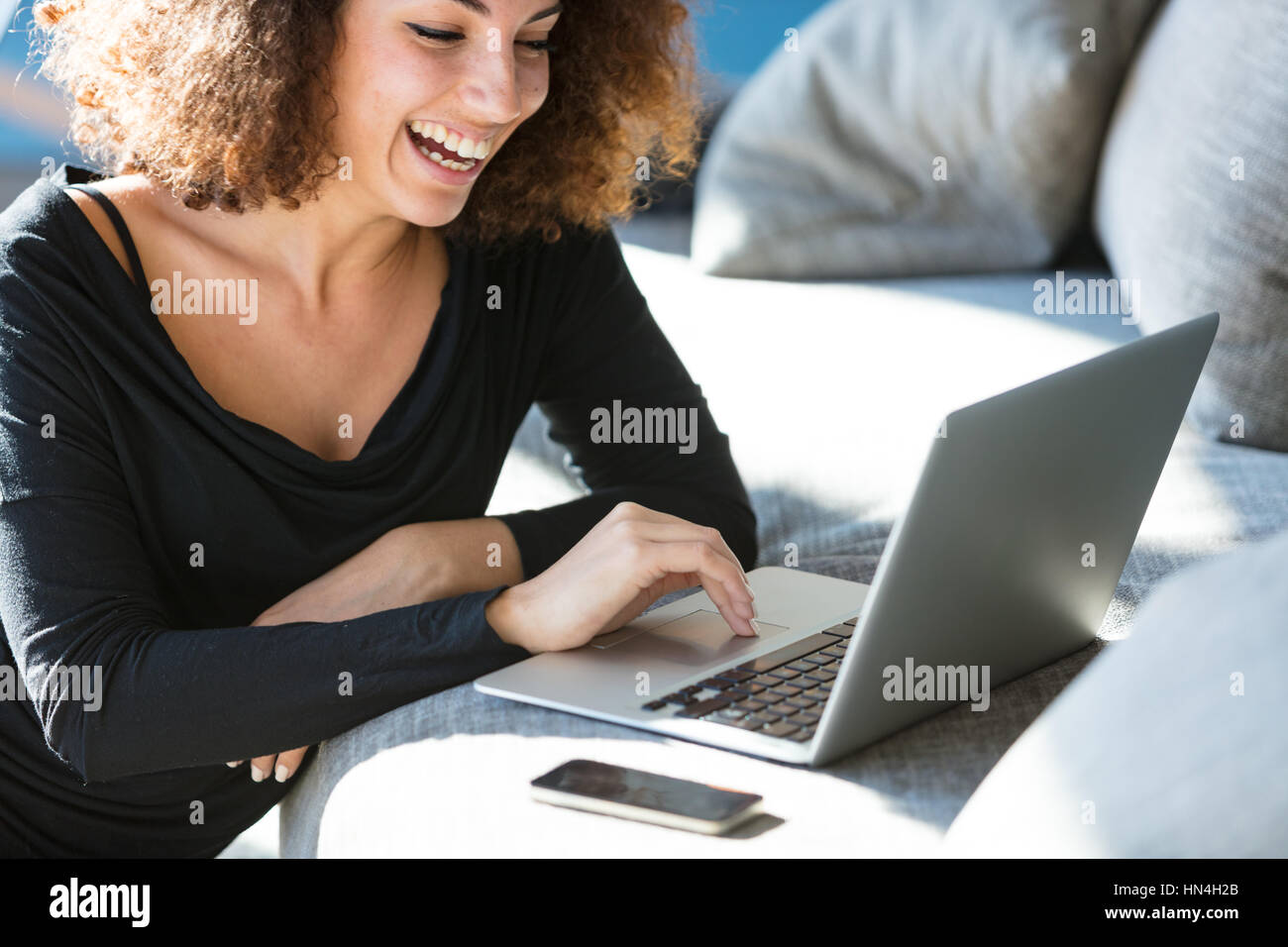 Happy young woman enjoying a good laugh as she surfs the internet on ...