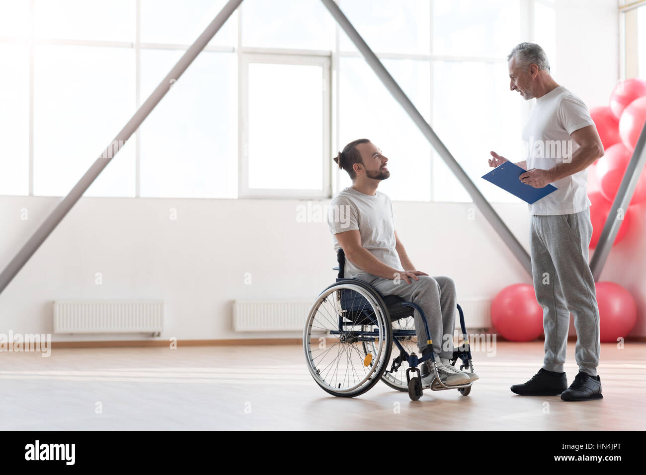 Smiling young disabled patient having conversation with his physical ...