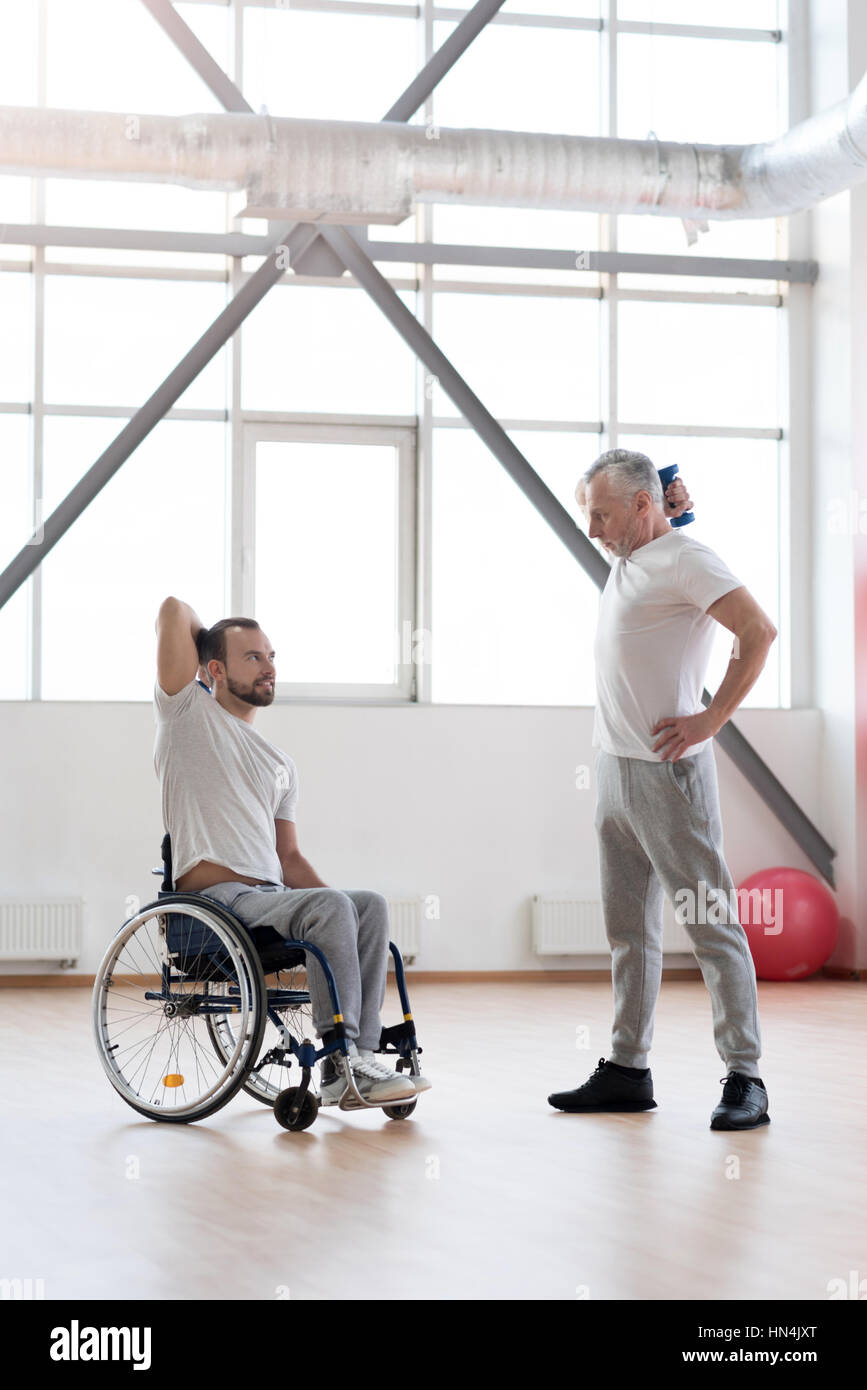 Athletic coach training the disabled young man in the gym Stock Photo ...