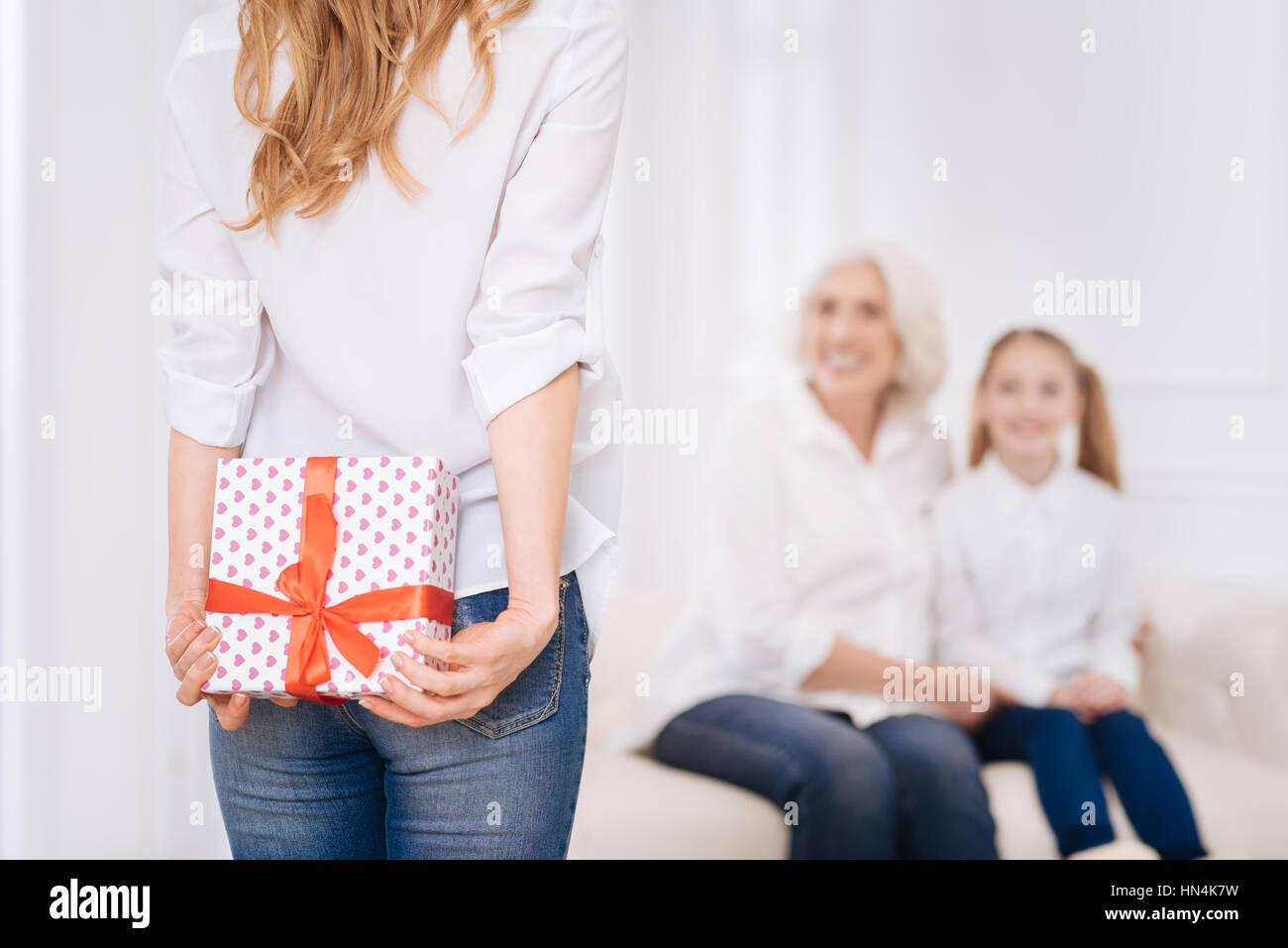 Pleasant adult woman holding present behind her back Stock Photo - Alamy