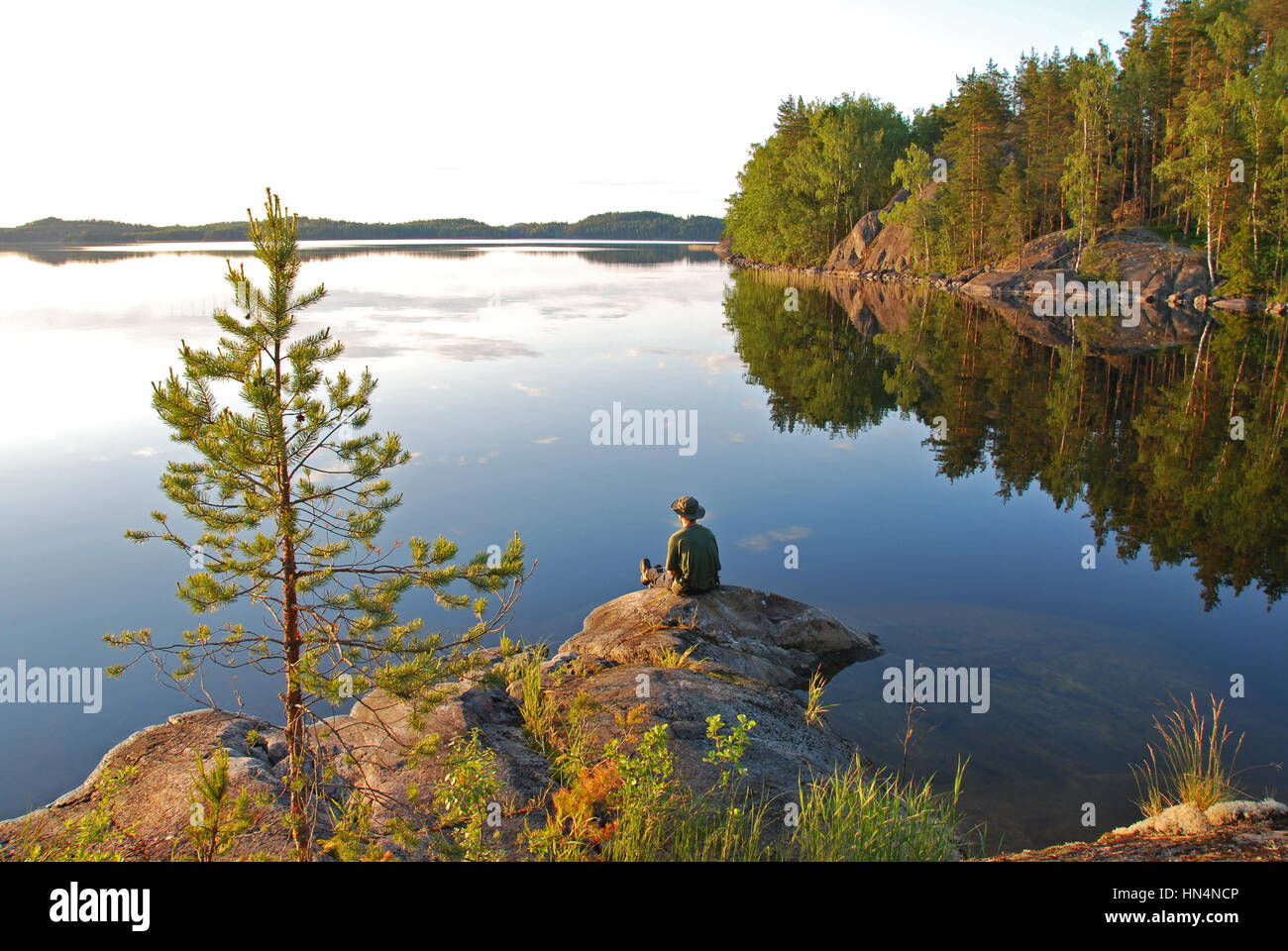 Man sitting at still Saimaa lake in Finland at sunset Stock Photo - Alamy