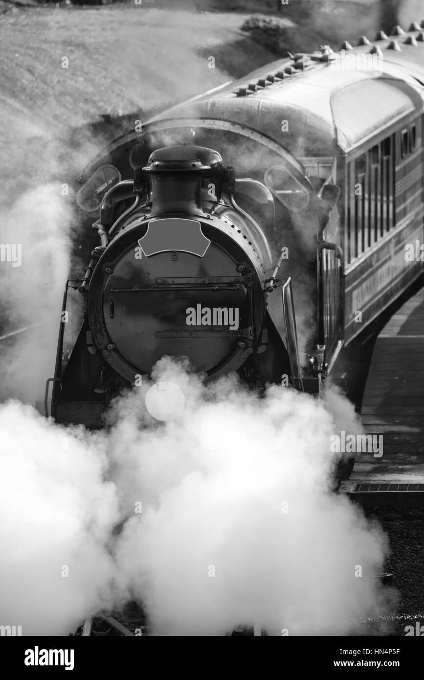 Victorian era steam train engine with full steam in black and white ...