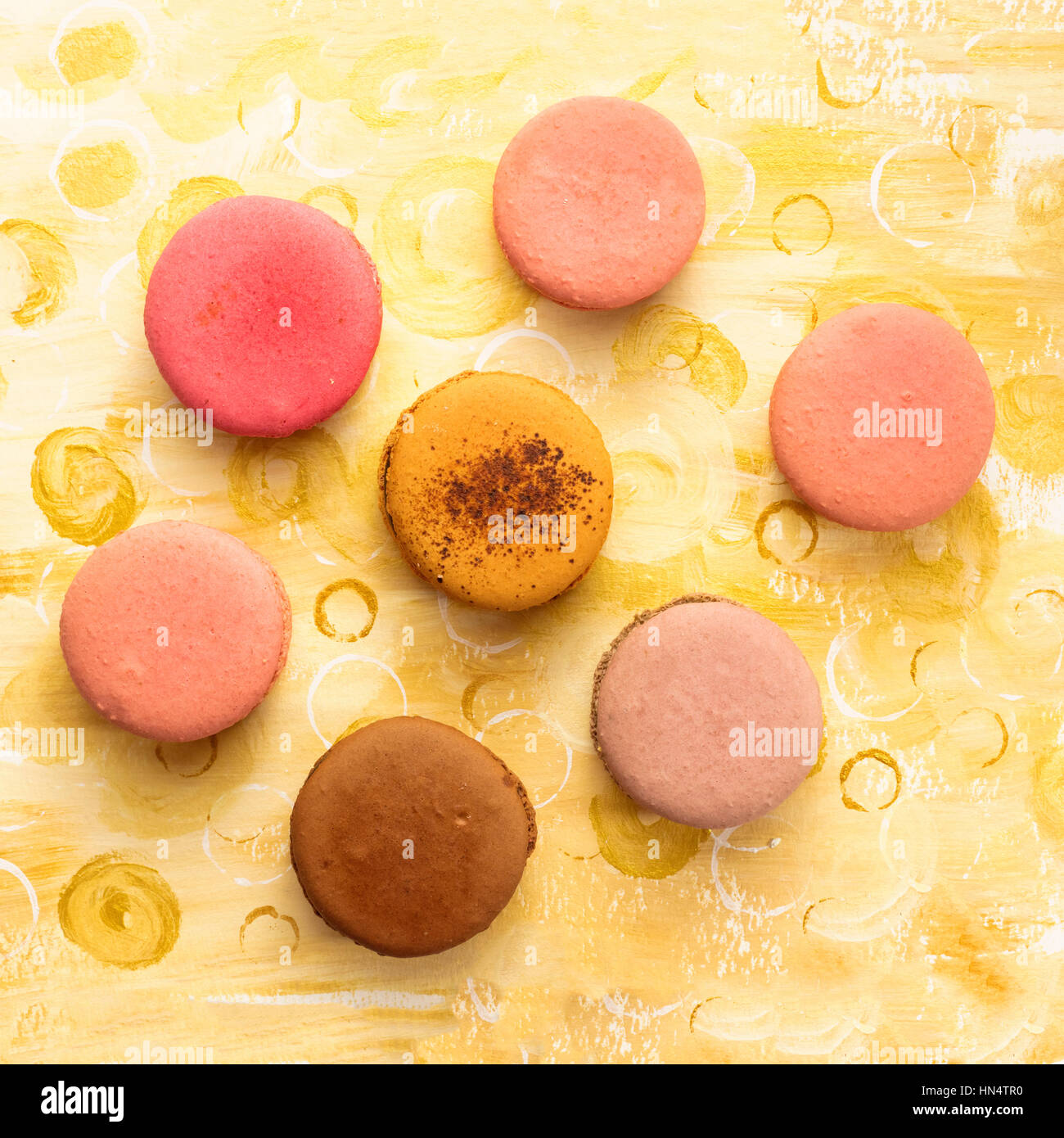 A photo of vibrant macarons, shot from above on a bright yellow ...