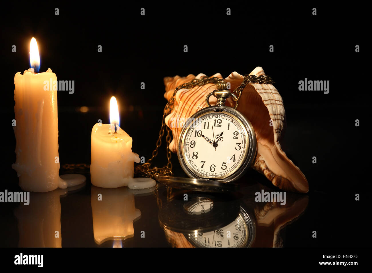 Vintage pocket watch near lighting candles and shell Stock Photo - Alamy