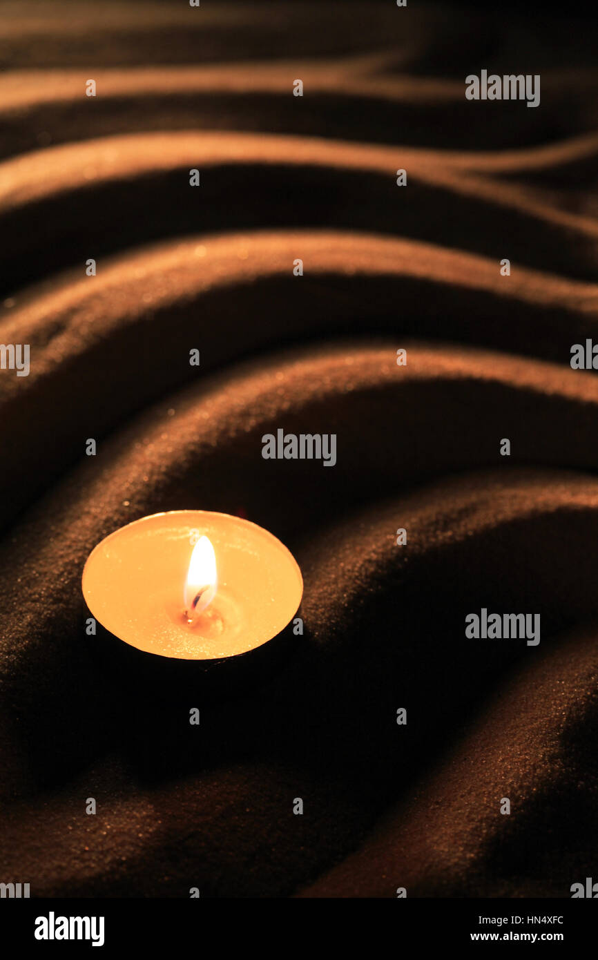 Lonely lighting candle on dark sand background Stock Photo - Alamy