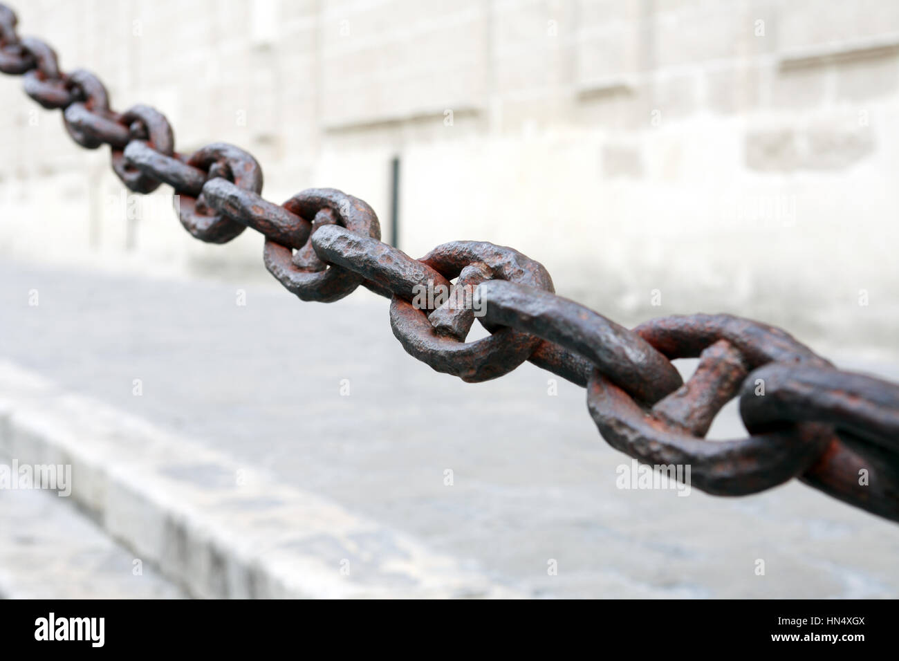 Old long rusty chain on gray building wall background Stock Photo - Alamy