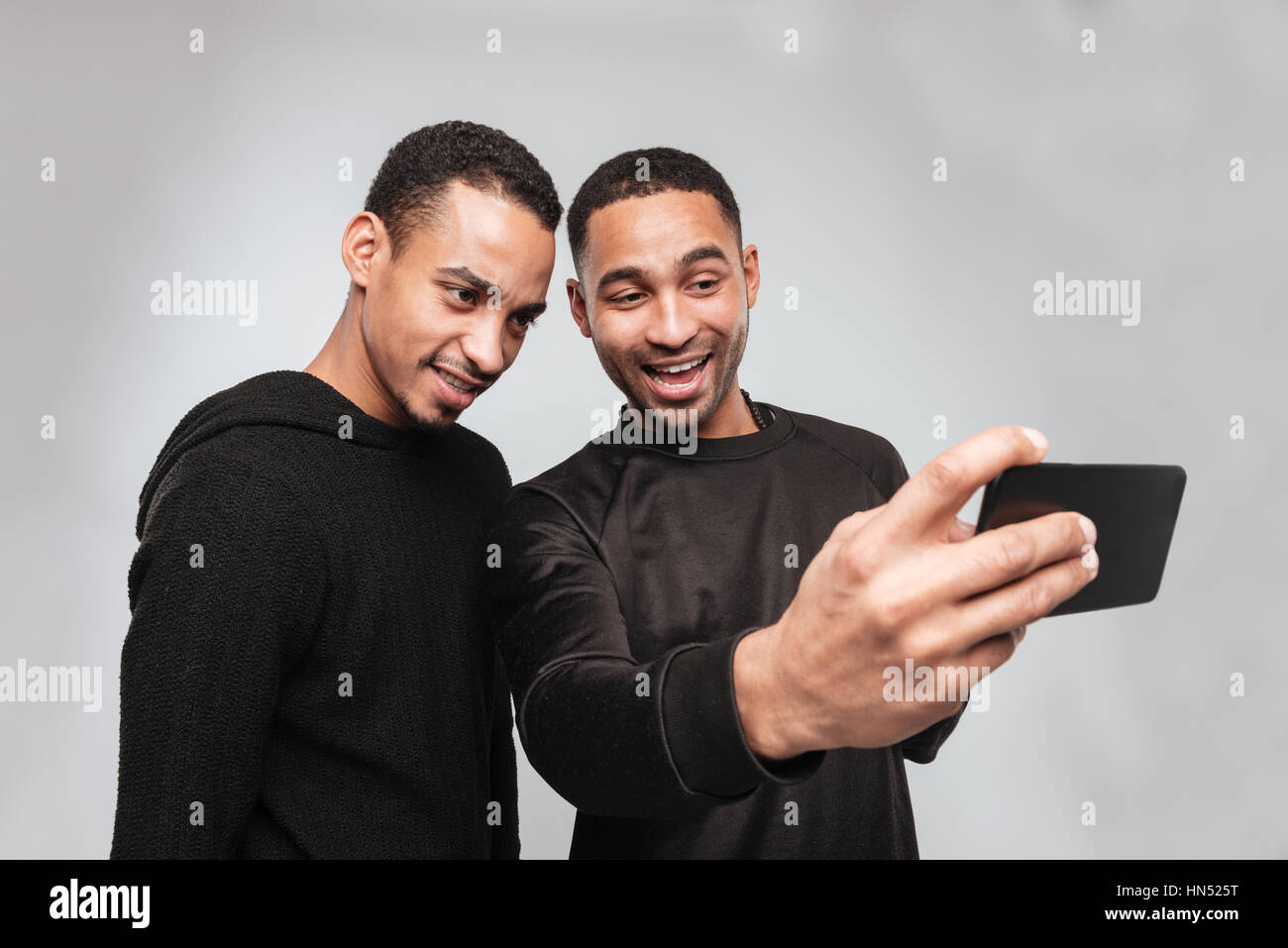 Picture of two young cheerful african men standing over white ...
