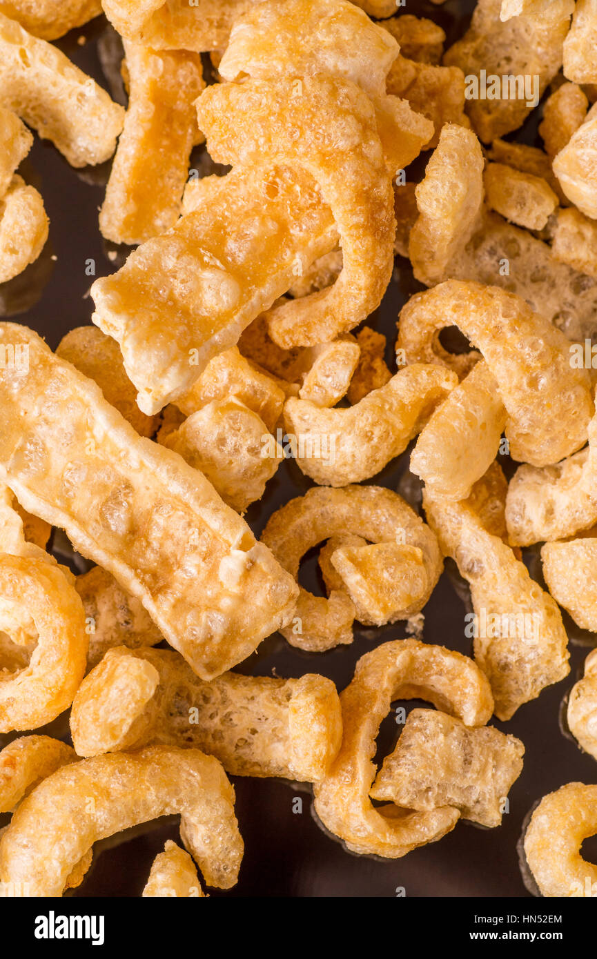 Delicious crispy pork rinds. A crisp salty snack on black glossy ...