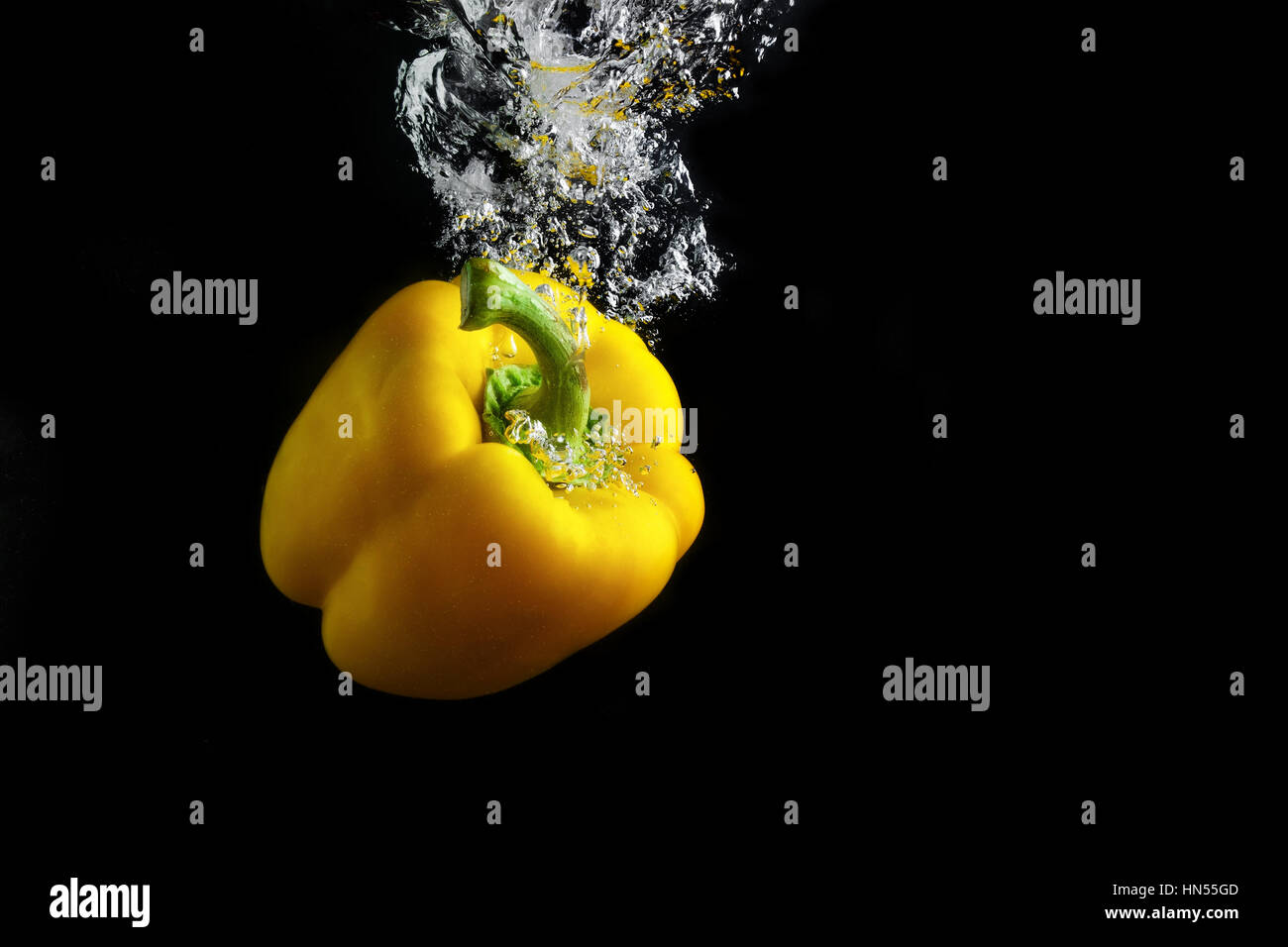 Fresh yellow paprika falling into the water with a splash and air ...