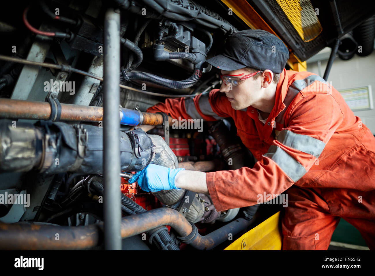 A young teenage apprentice fitter mechanic fixing broken down double ...
