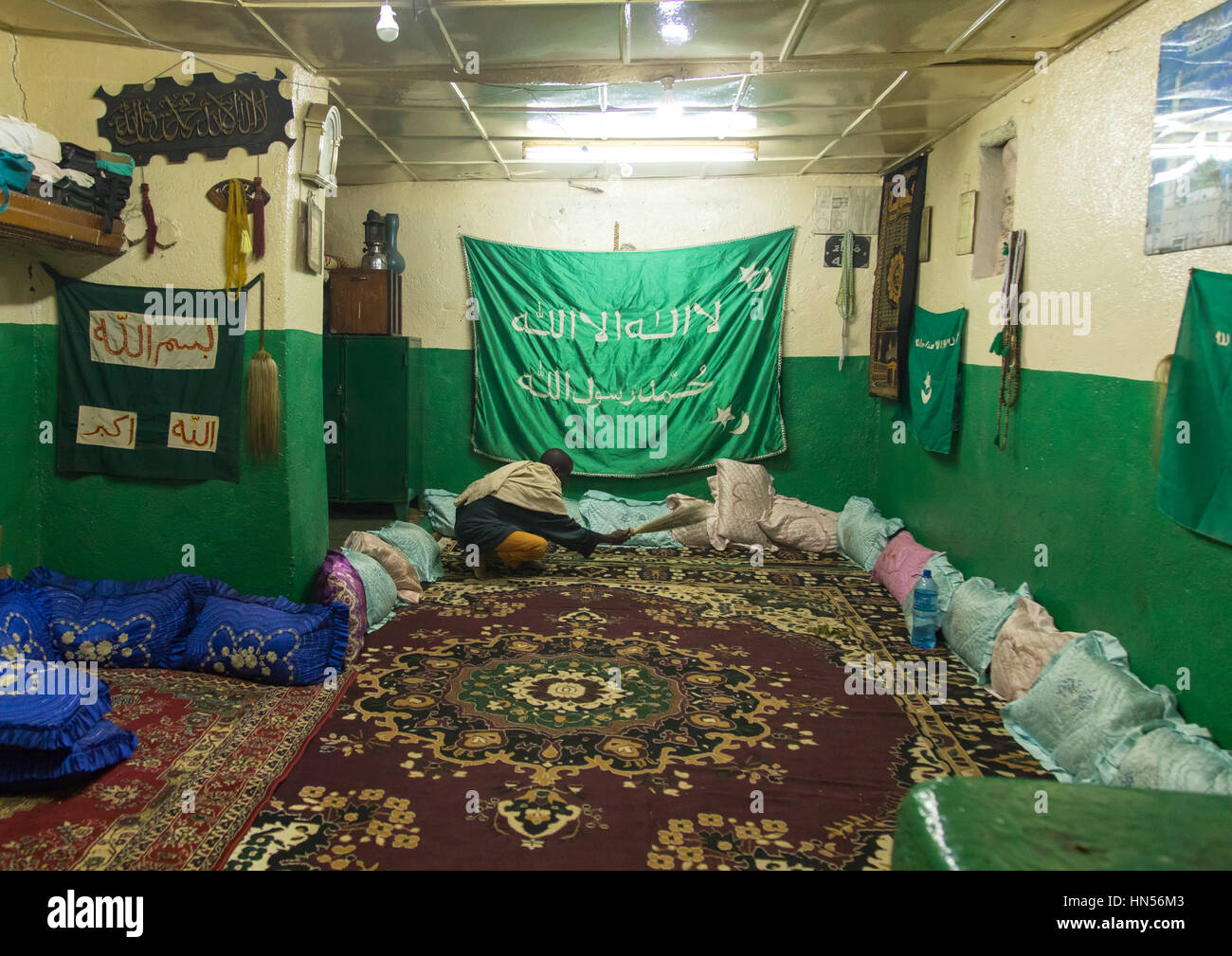 Man cleaning a room decorated with islam flags before a sufi ...