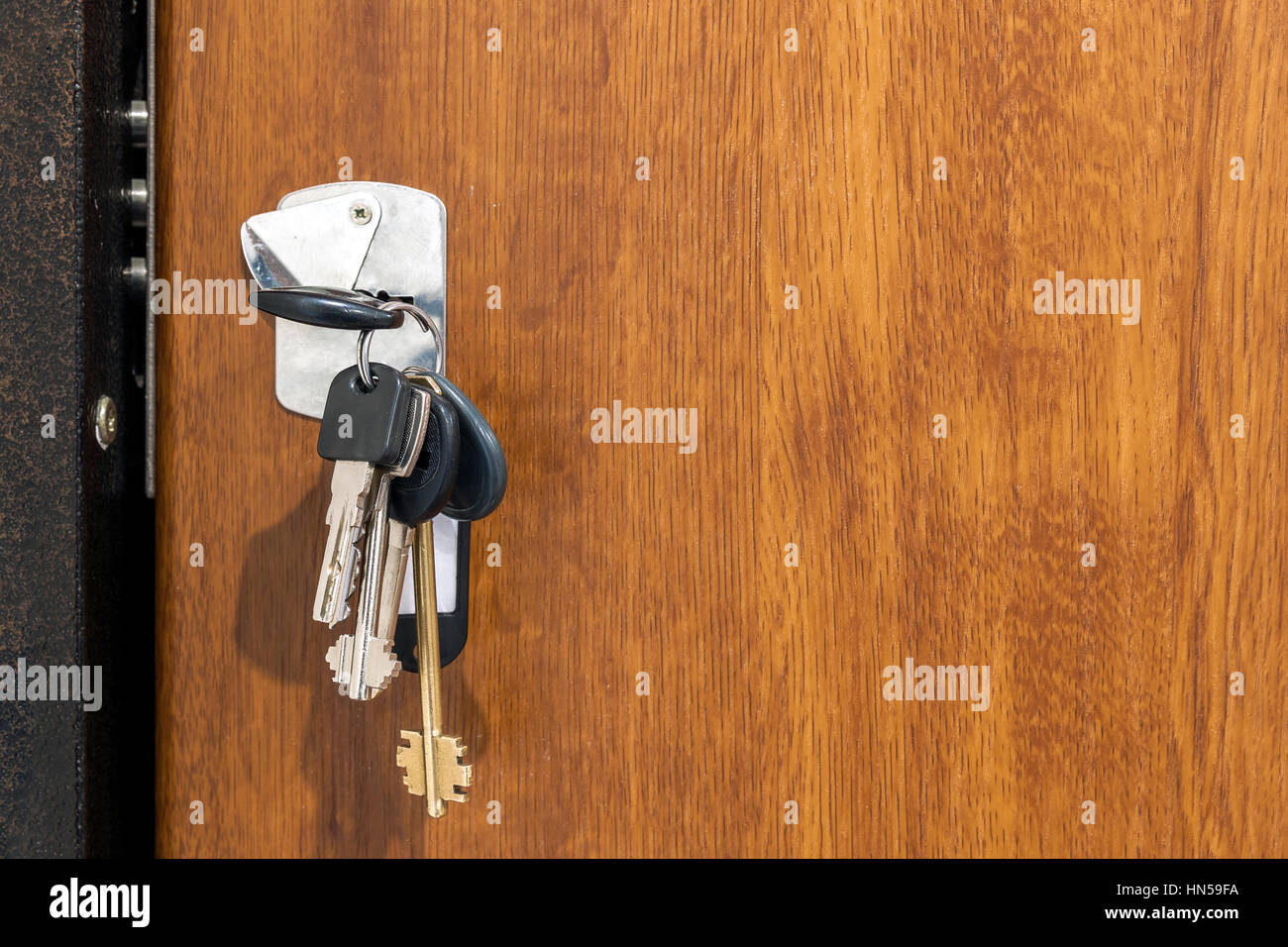 Close-up of bundle of different keys in key hole in wooden texture door ...