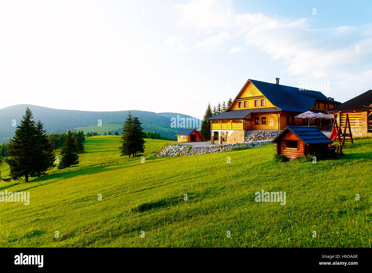 Rural cottage in the mountains and green meadow. Sunset scenery ...