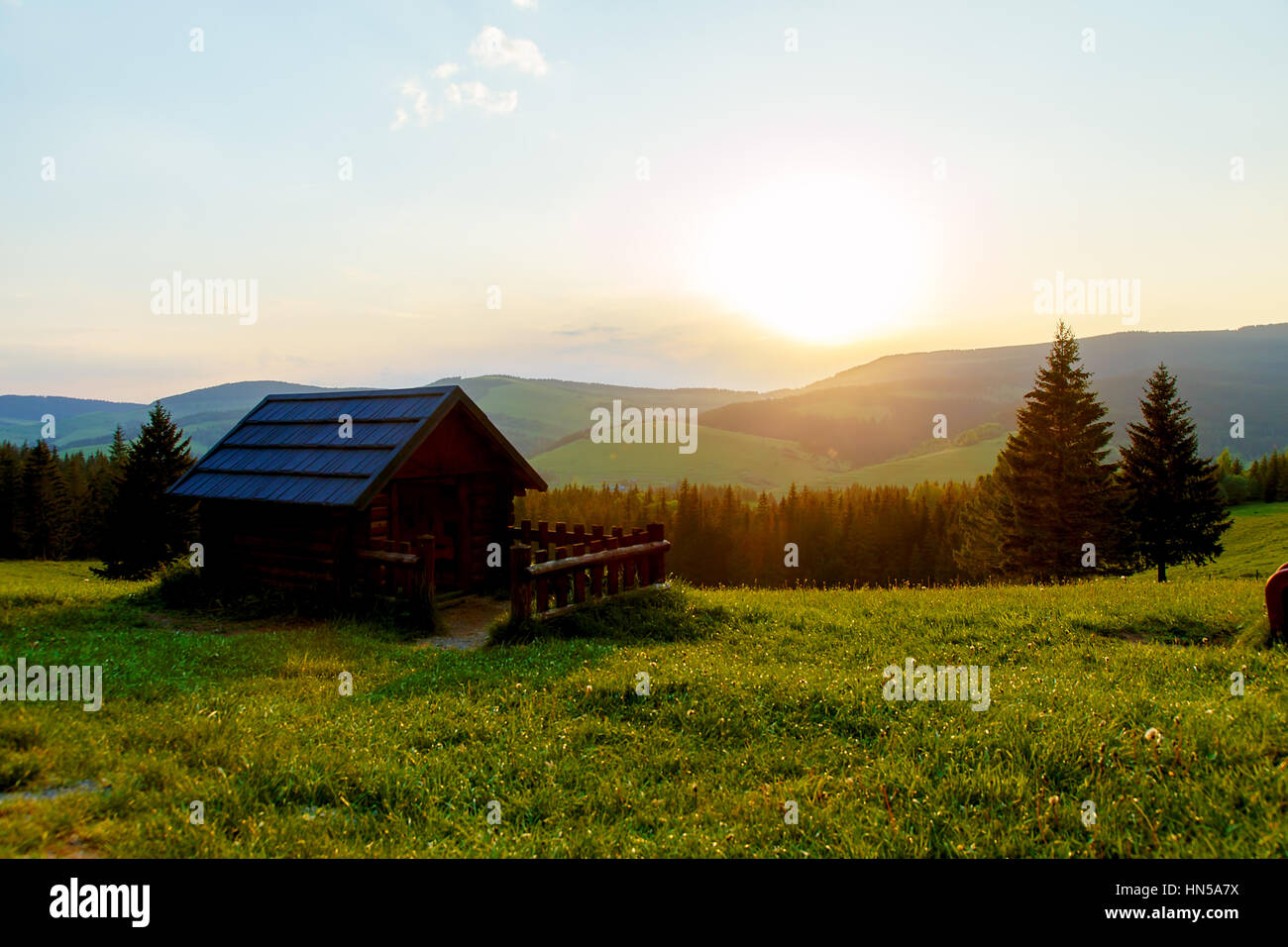 Rural cottage in the mountains and green meadow. Sunset scenery ...