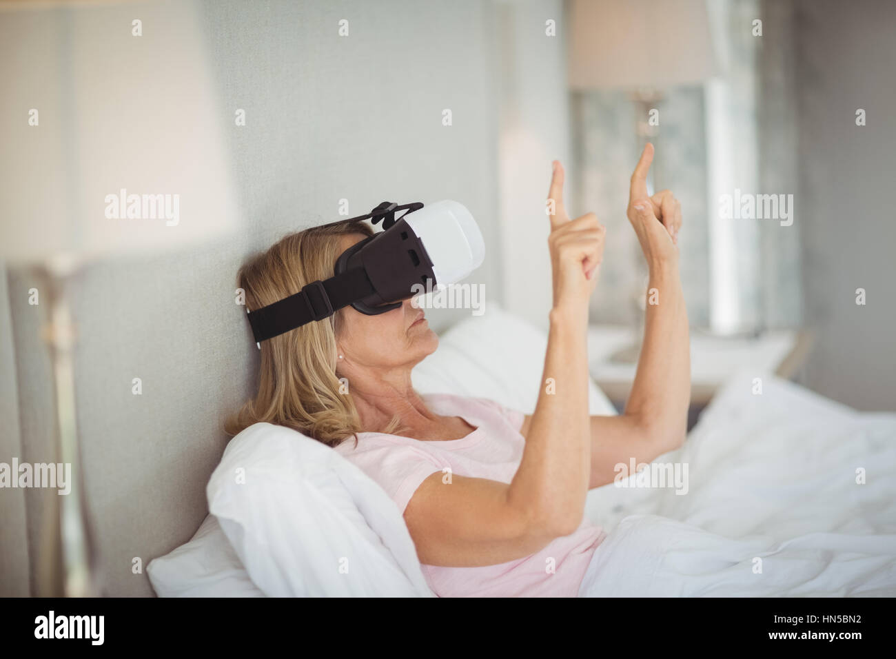 Senior woman lying on bed and using virtual reality headset Stock Photo ...