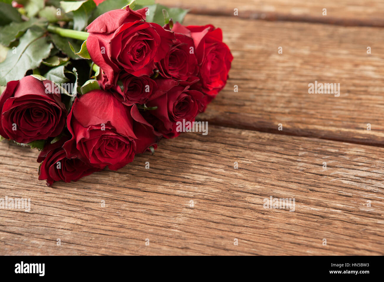 Bunch of red roses and gift box against wooden background Stock Photo ...
