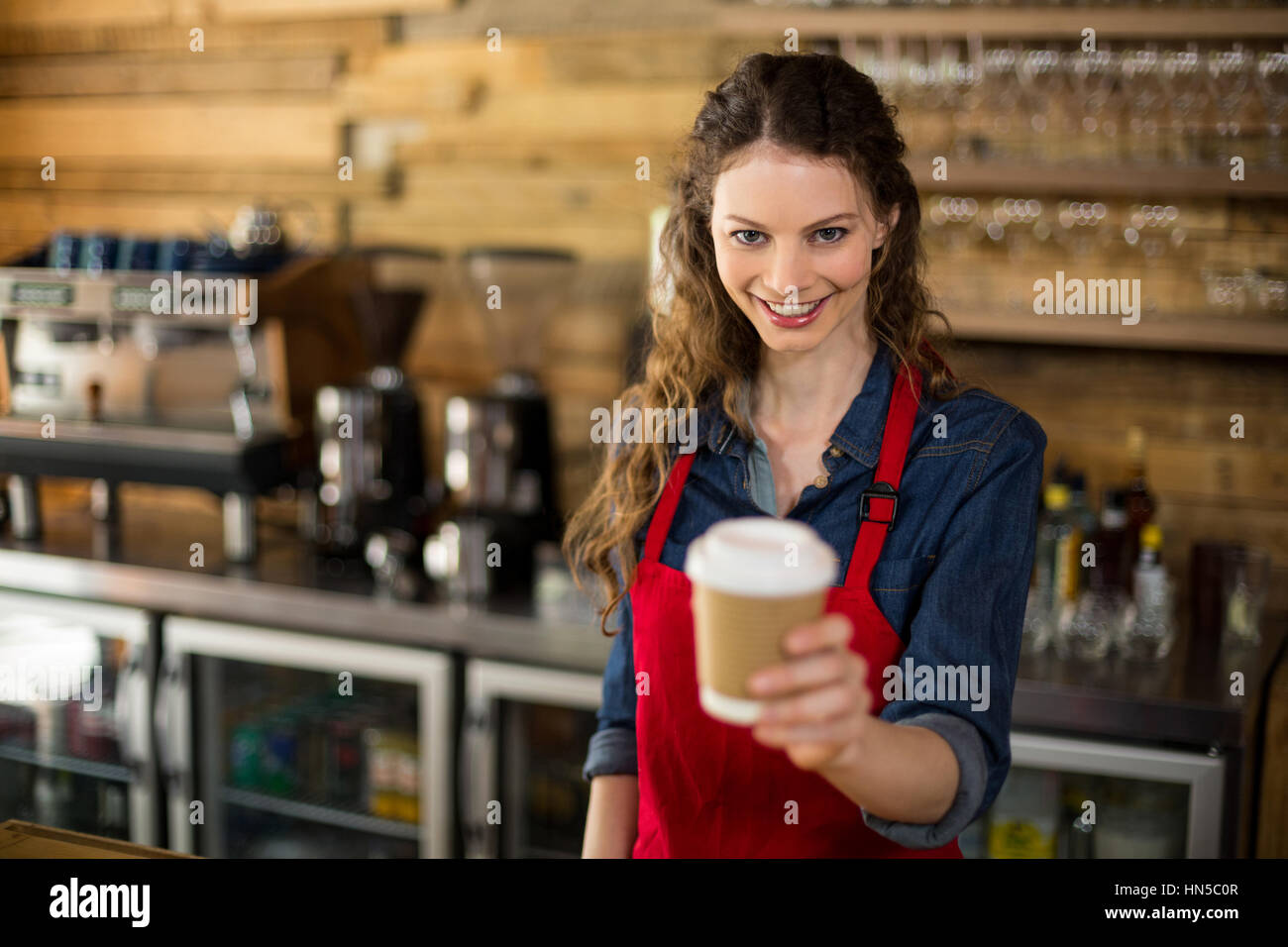 Portrait of smiling waitress serving a cup of coffee to customer in ...