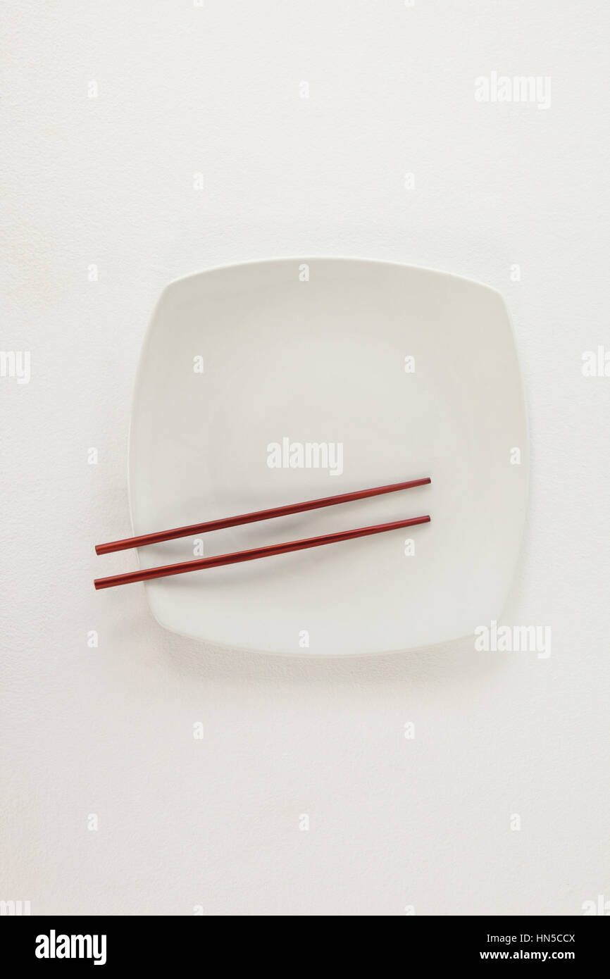 Pair of chopsticks on a plate against white background Stock Photo - Alamy