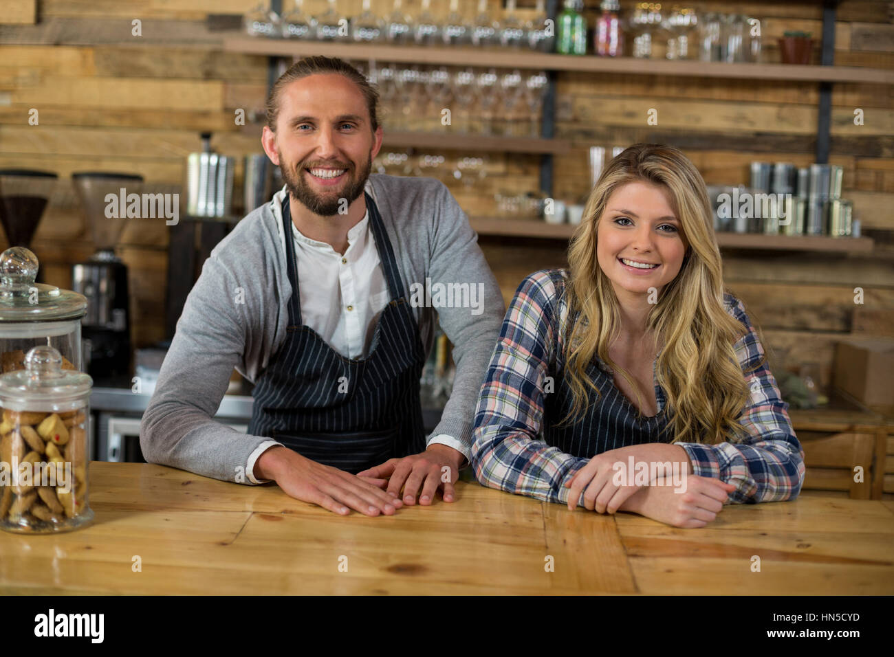 Portrait of smiling waiter and waitress leaning at counter in cafÃƒÂ ...