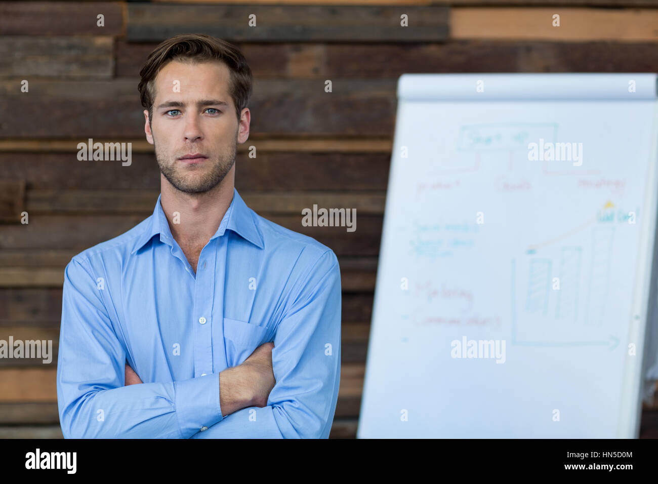 Portrait of male business executive standing with arms crossed in ...