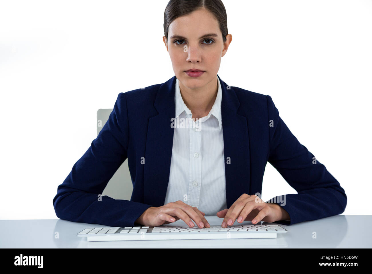Portrait of businesswoman typing on keyboard at desk against white ...