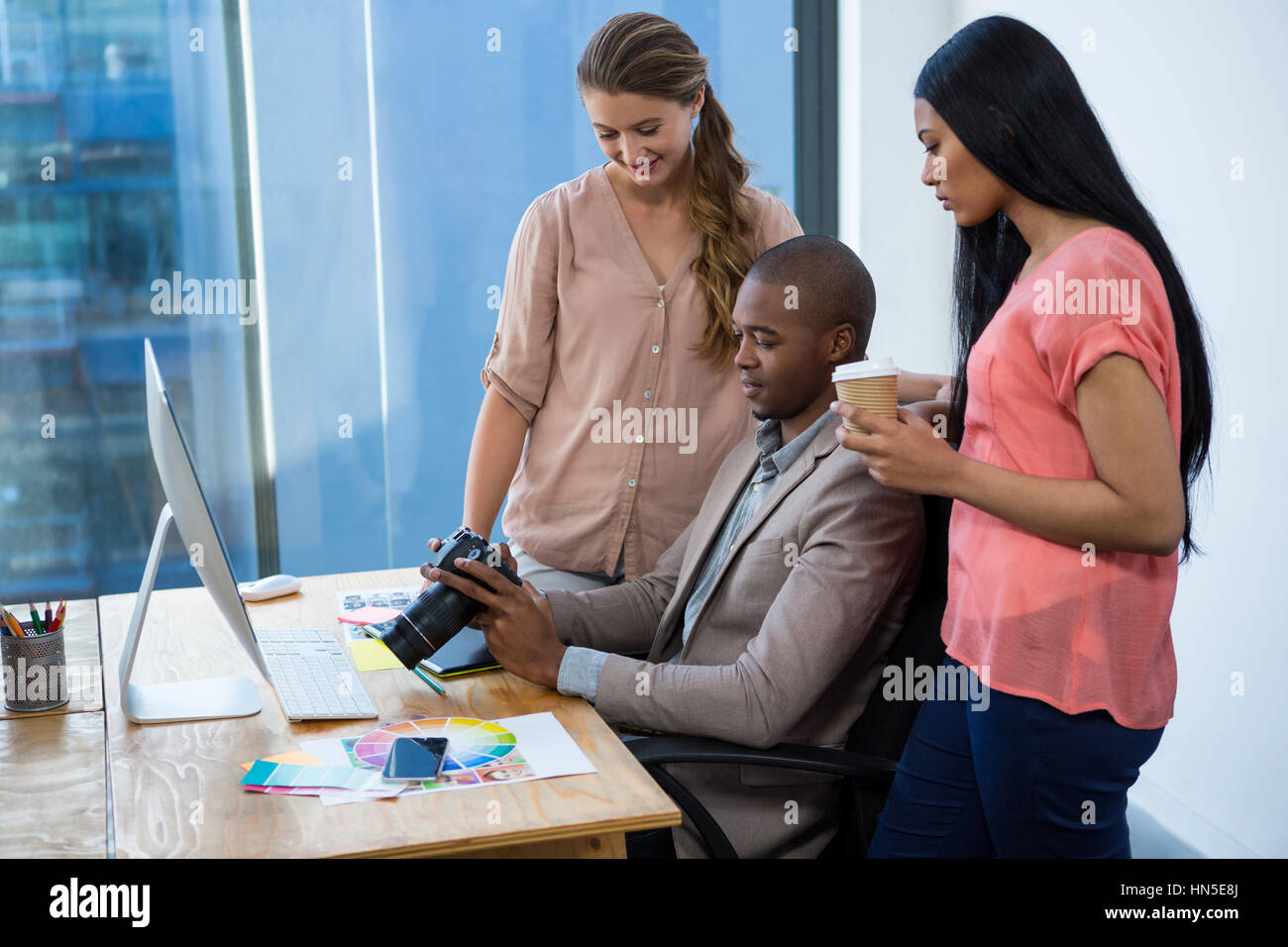 Graphic designer reviewing photos in camera with colleagues in office ...