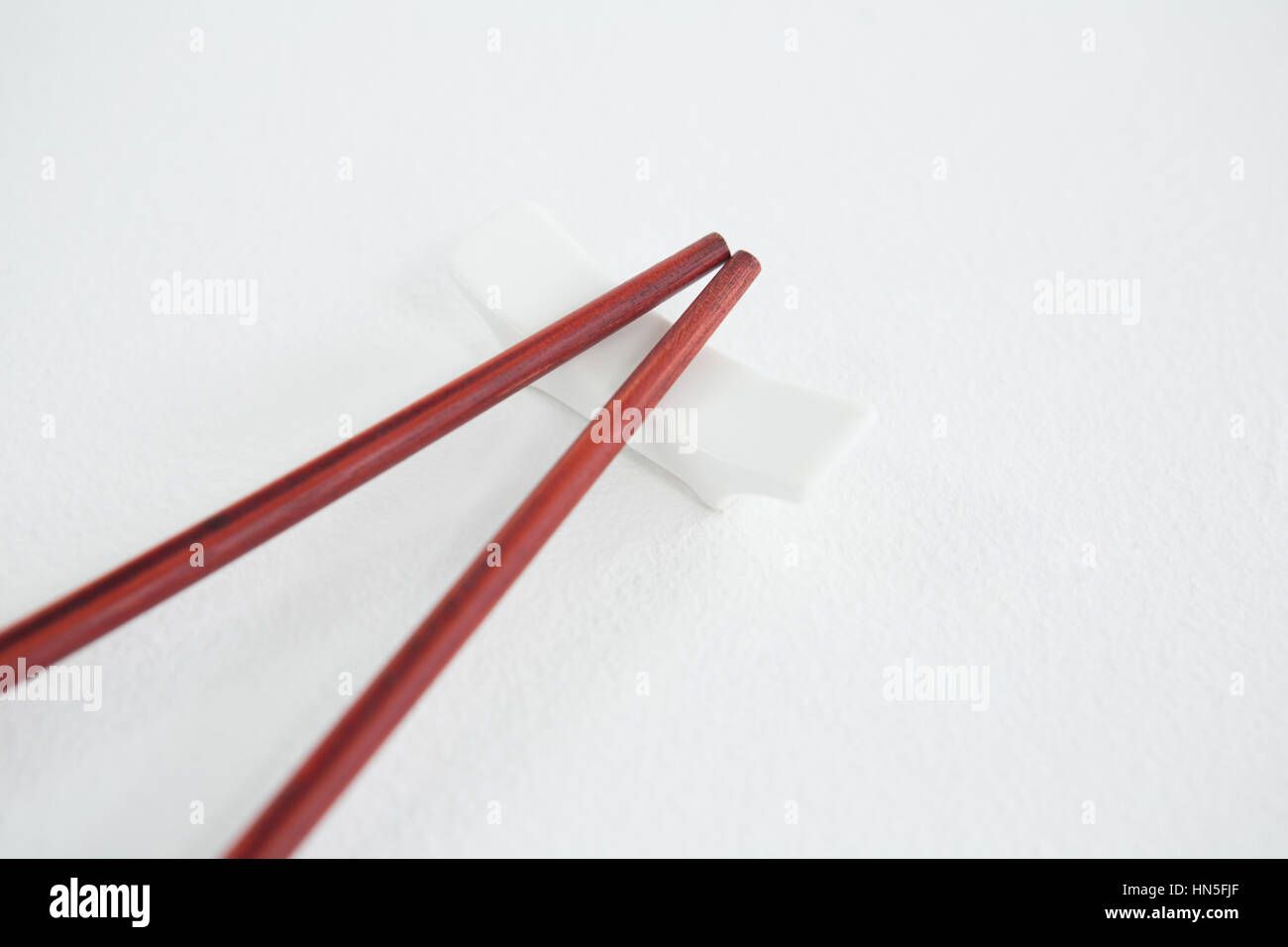 Red chopsticks on a chopstick rest against white background Stock Photo ...
