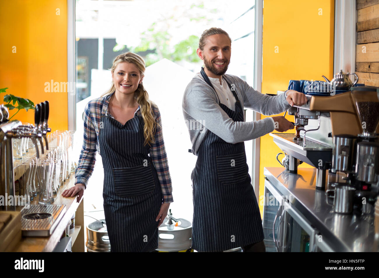 Portrait of smiling waitress and waiter working at counter in cafÃƒÂ ...