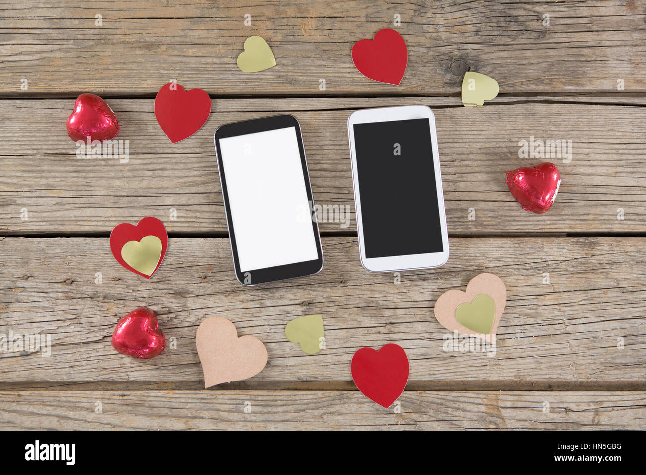 Mobile phone surrounded with heart shape decoration on wooden surface ...
