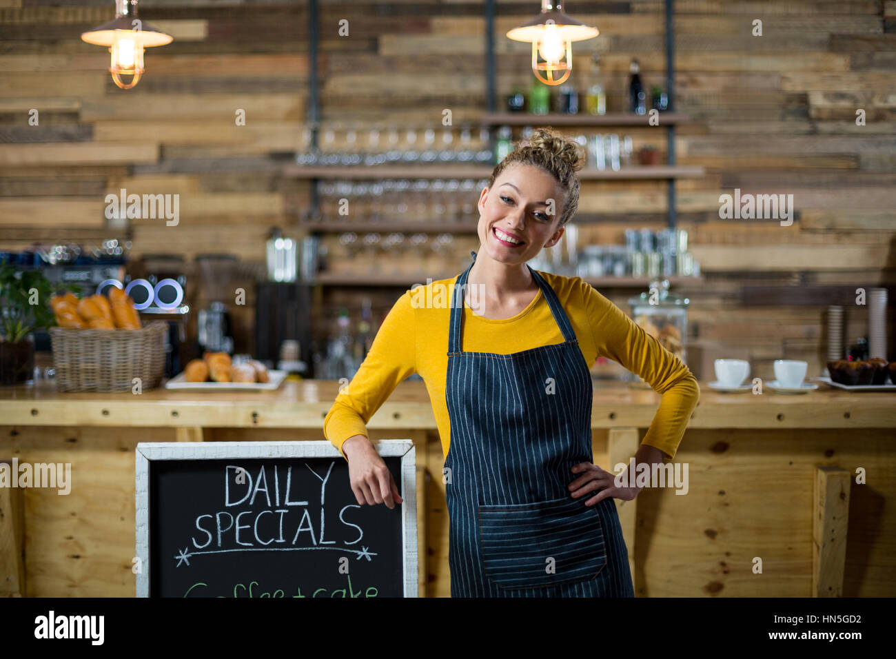 Portrait of smiling waitress standing with menu board in cafe Stock ...