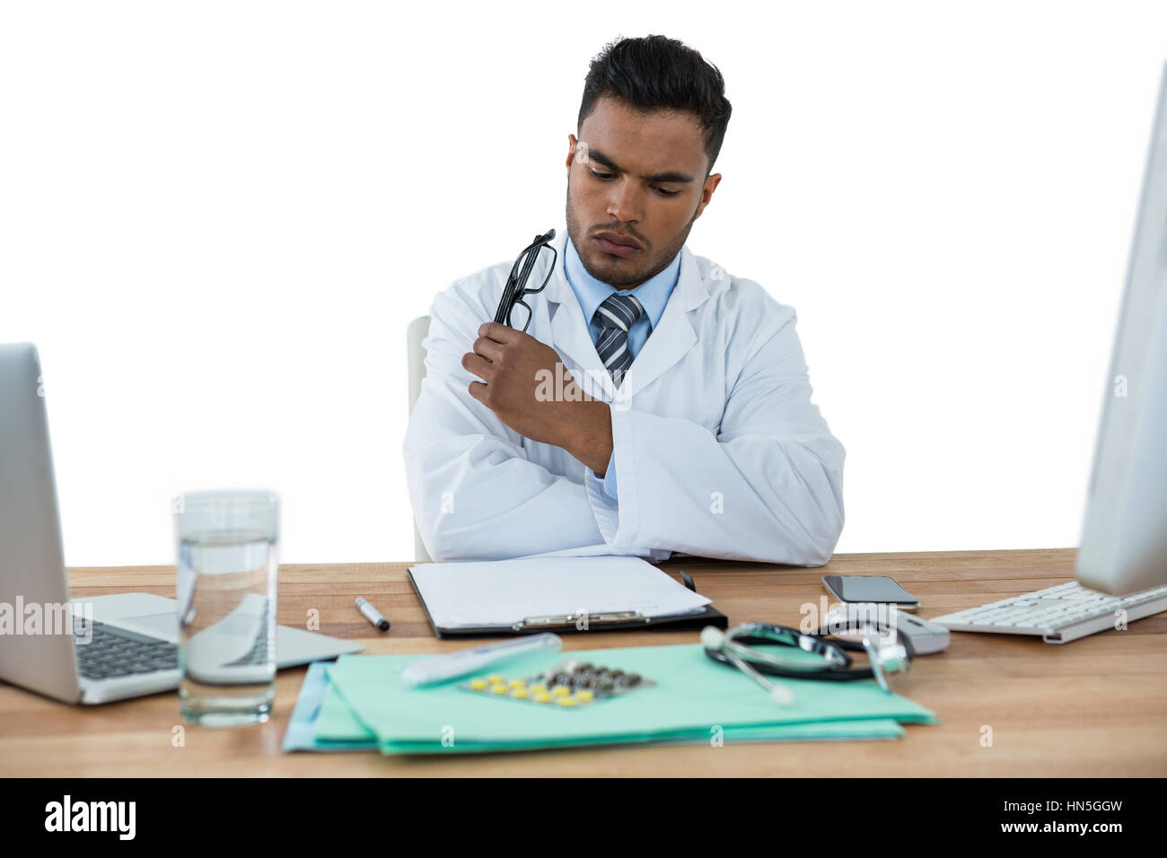 Doctor looking medical report at desk against white background Stock ...