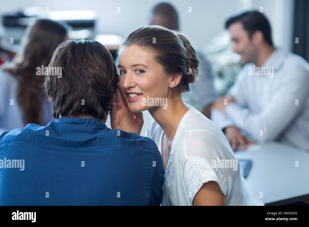 Female business executive whispering to her colleague in office Stock ...