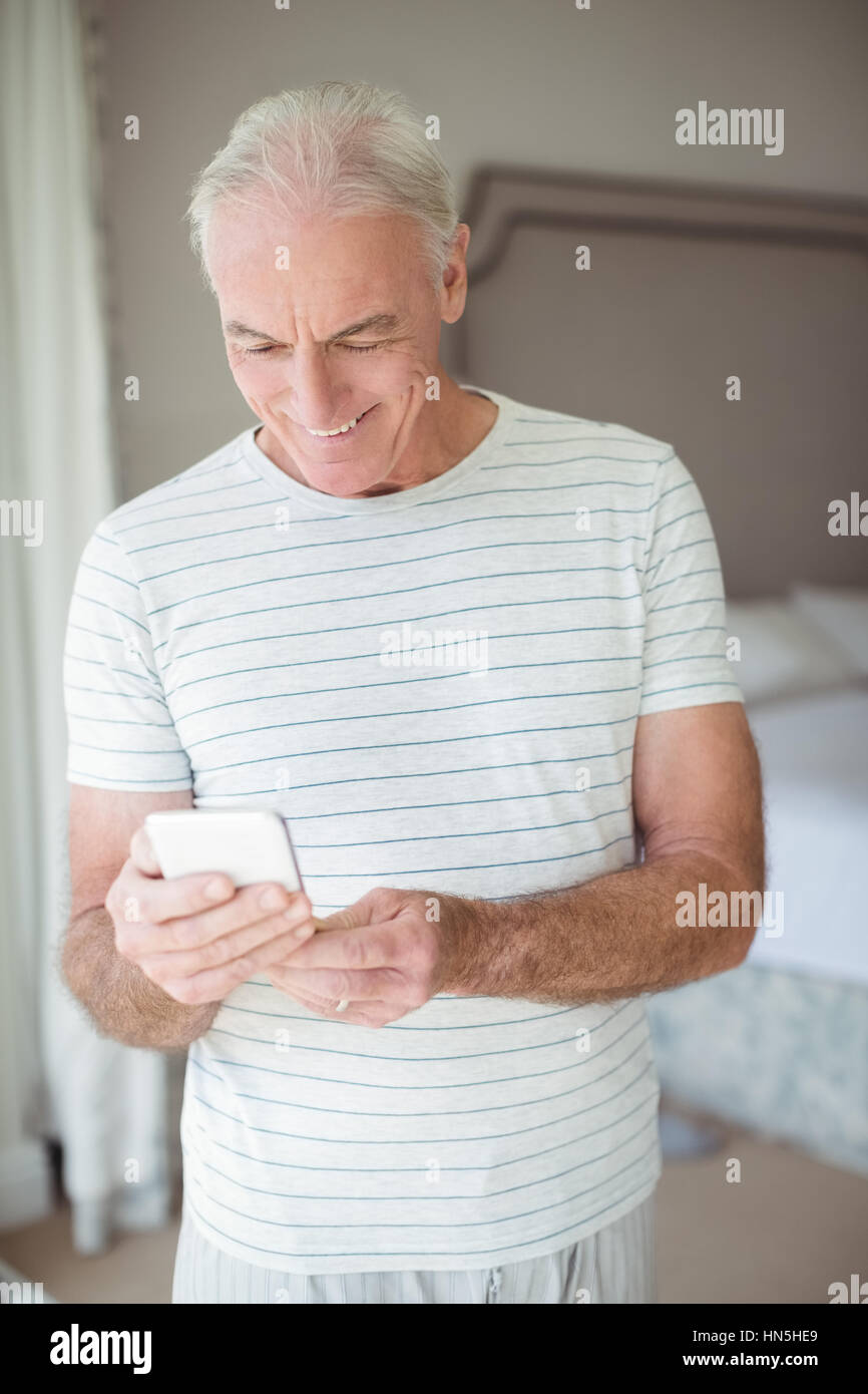 Happy senior man using mobile phone in bedroom at home Stock Photo - Alamy