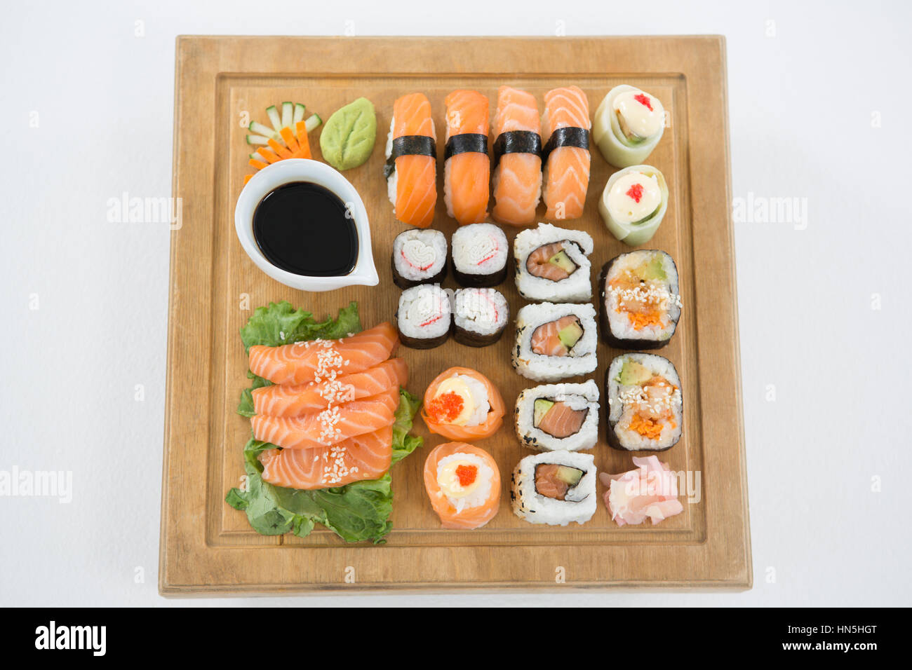 Set of assorted sushi served on wooden tray against white background ...