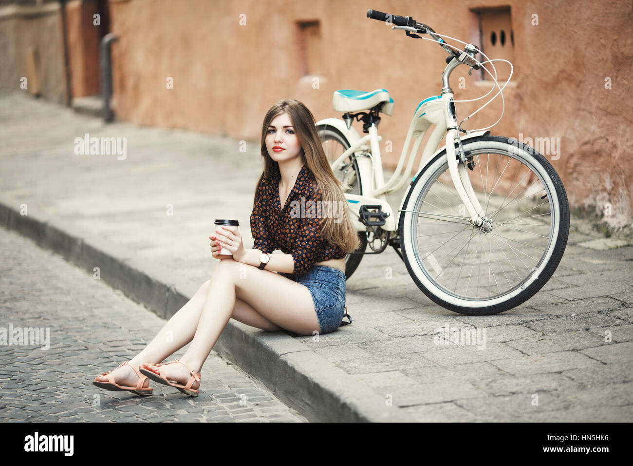 Beautiful young woman is posing with coffee on tiled pavement on the ...