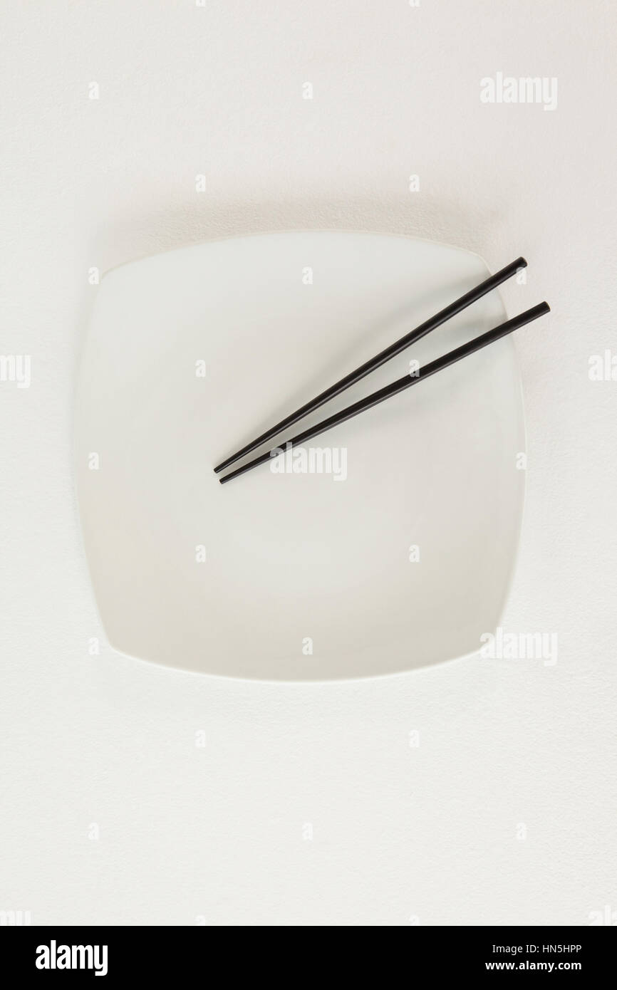 Pair of chopsticks on a plate against white background Stock Photo - Alamy
