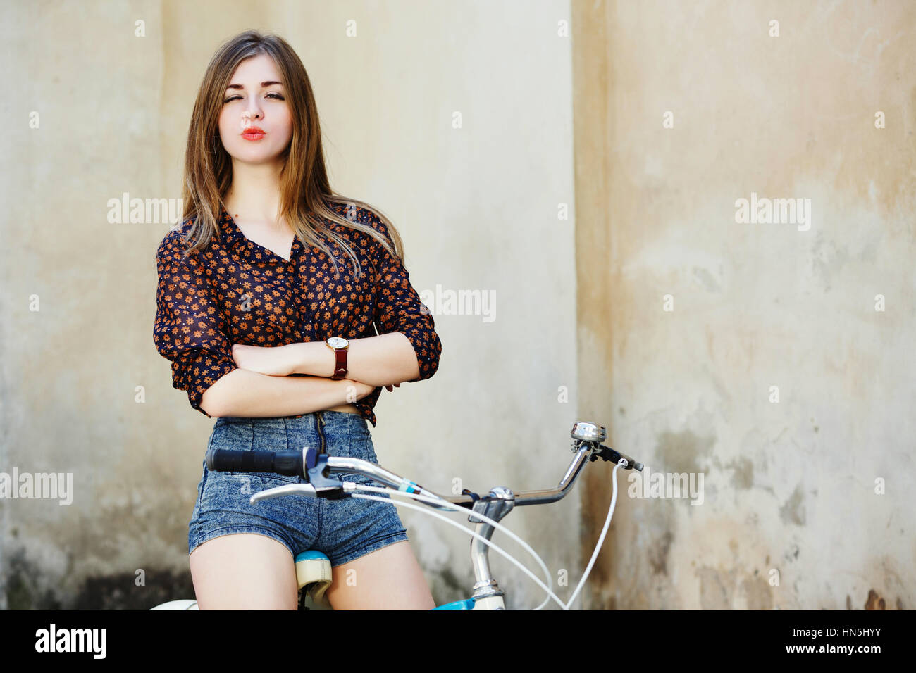 Happy young woman with long hair is posing on the bicycle on the old ...