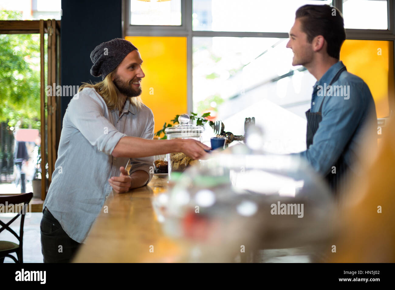 Smiling waiter serving cup of coffee to man at counter in cafÃƒÂ© Stock ...
