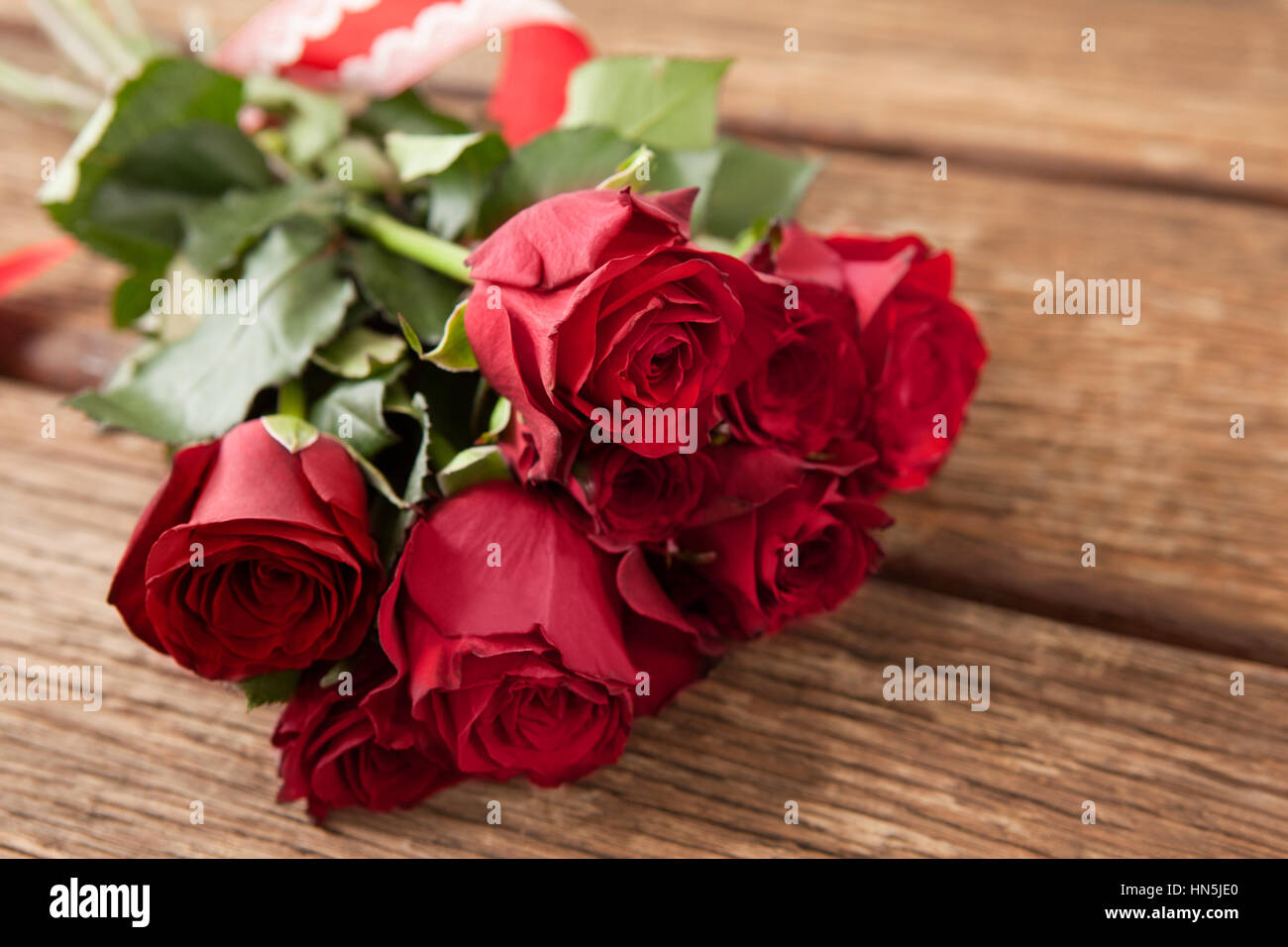 Bunch of red roses and gift box against wooden background Stock Photo ...