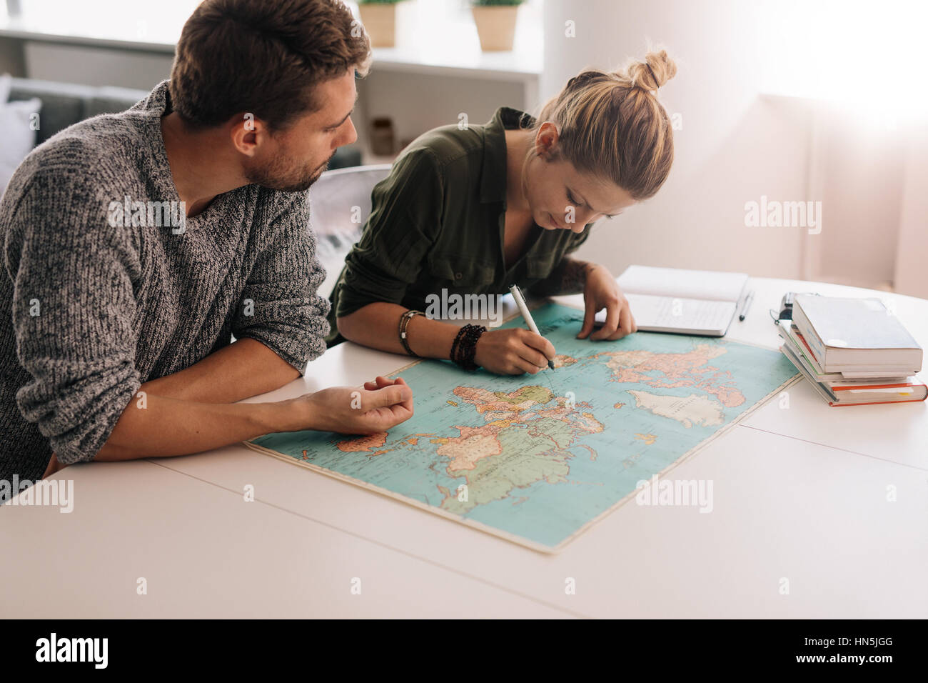 Man and woman studying the world map and taking notes. Woman marking on ...