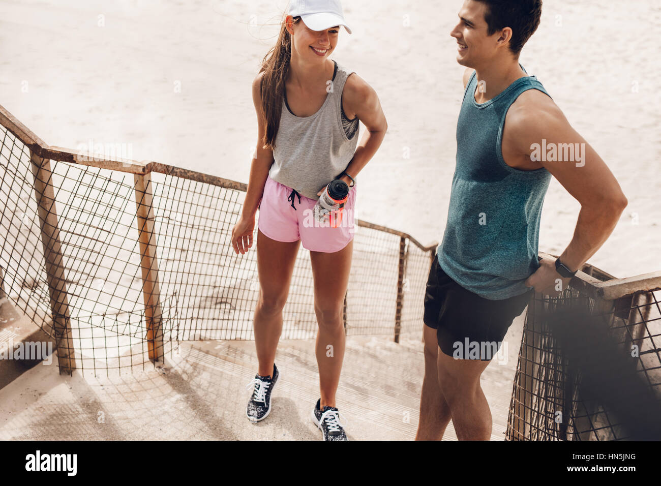 Happy young man and woman taking break after running session in morning ...
