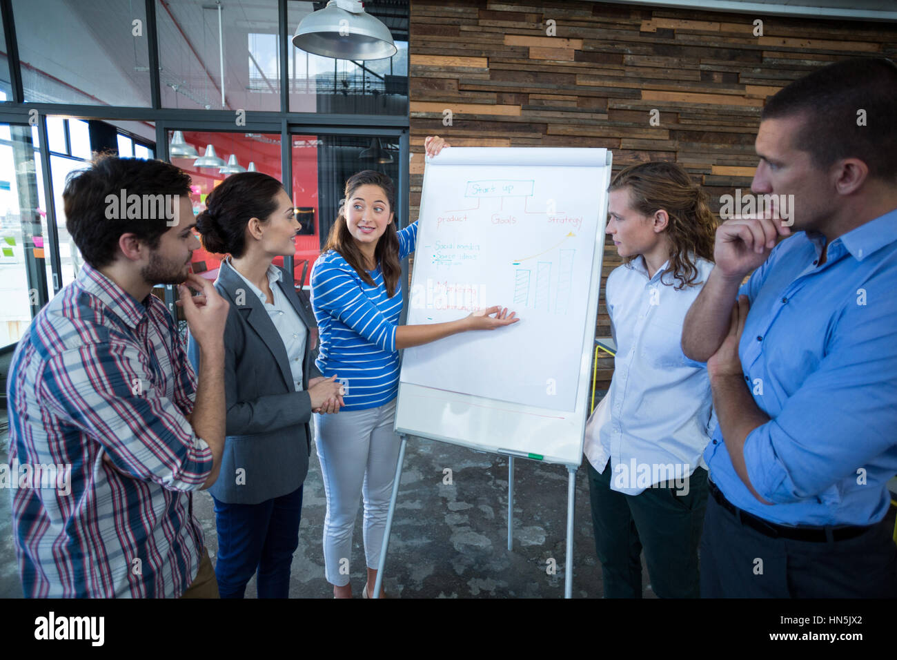 Team of businesspeople having discussion over flip chart in office ...