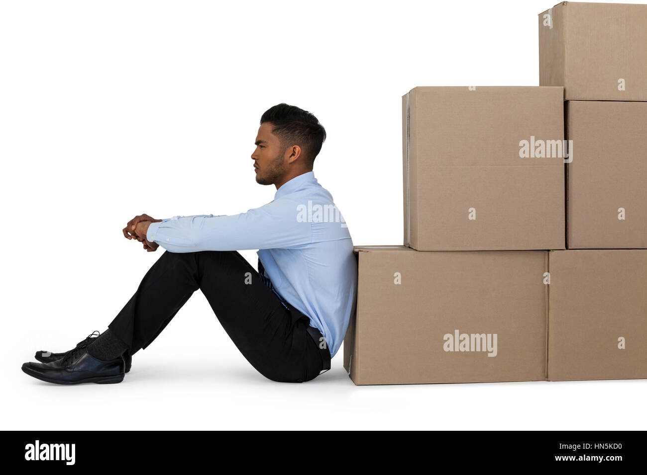 Thoughtful businessman leaning on cardboard boxes against white ...